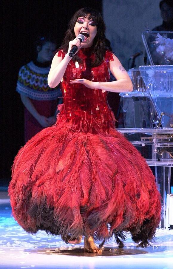 Bjork wears a green feathered dress and dramatic make-up as she reveals ...