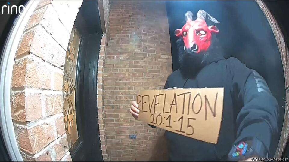 Unknown man wearing satanic mask, holding sign with apocalyptic Bible ...