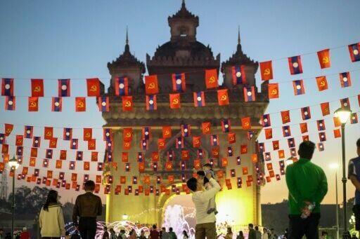 People walking under Laos national flags and Lao People's Revolutionary ...