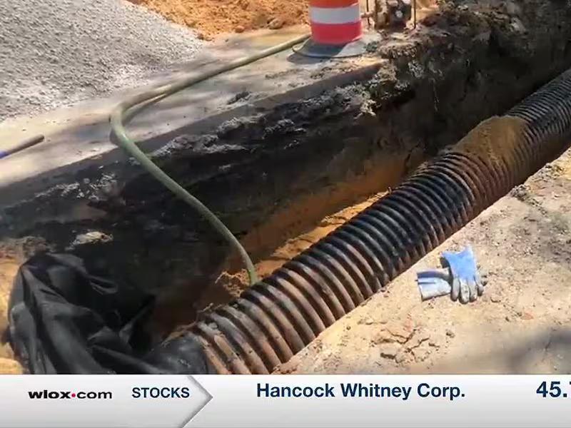 Workers install drainage pipe under Martin Bluff Road to stop flooding ...