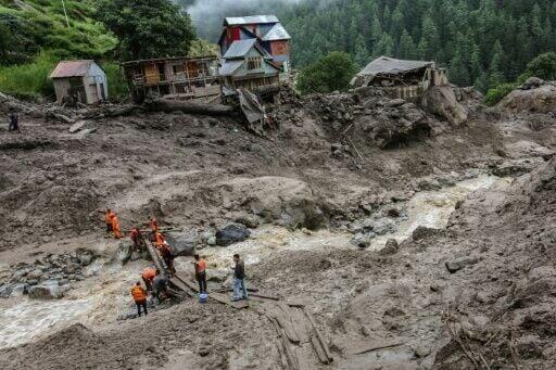 Rescuers work at the site of a flash flood at a village in Indian ...